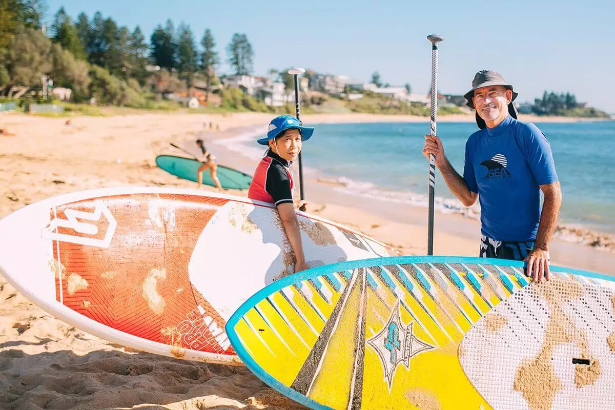 mennesker med paddle boards stående på toowoon bay stranden