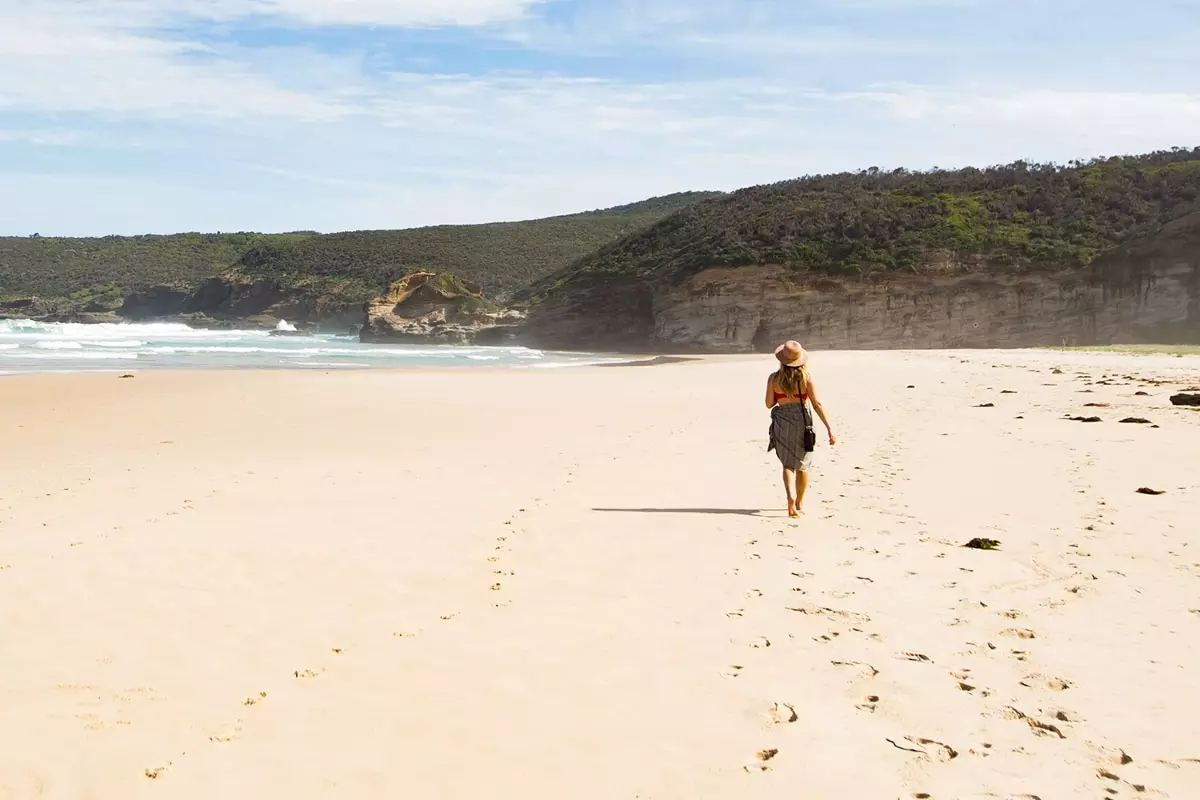 mujer caminando en la playa de madera