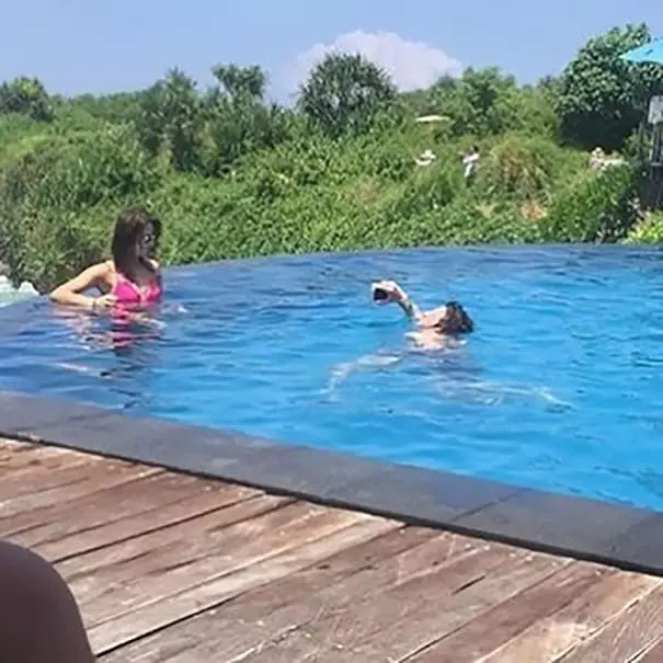 las mujeres capturan su imagen de pie en la piscina