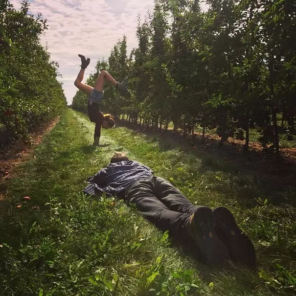 homem tirando foto da namorada no pomar