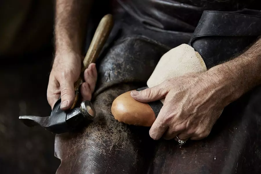 een schoenmaker die de zool van een schoen repareert