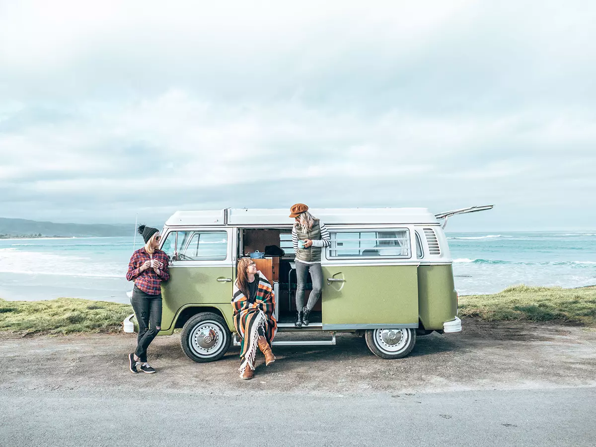 teman bahagia di mobil minivan di pantai