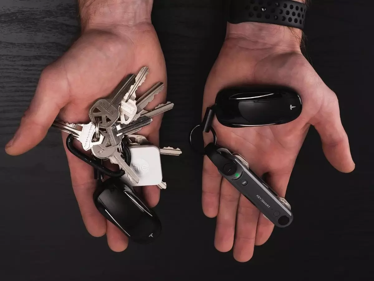 man hâldt keysmart max mei ynboude tegeltracker en toetsen yn hannen