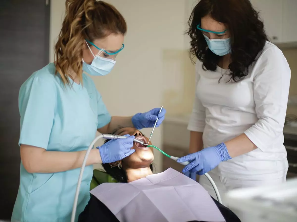 лекар лечыць зубы пацыента ў бары ўсмешкі