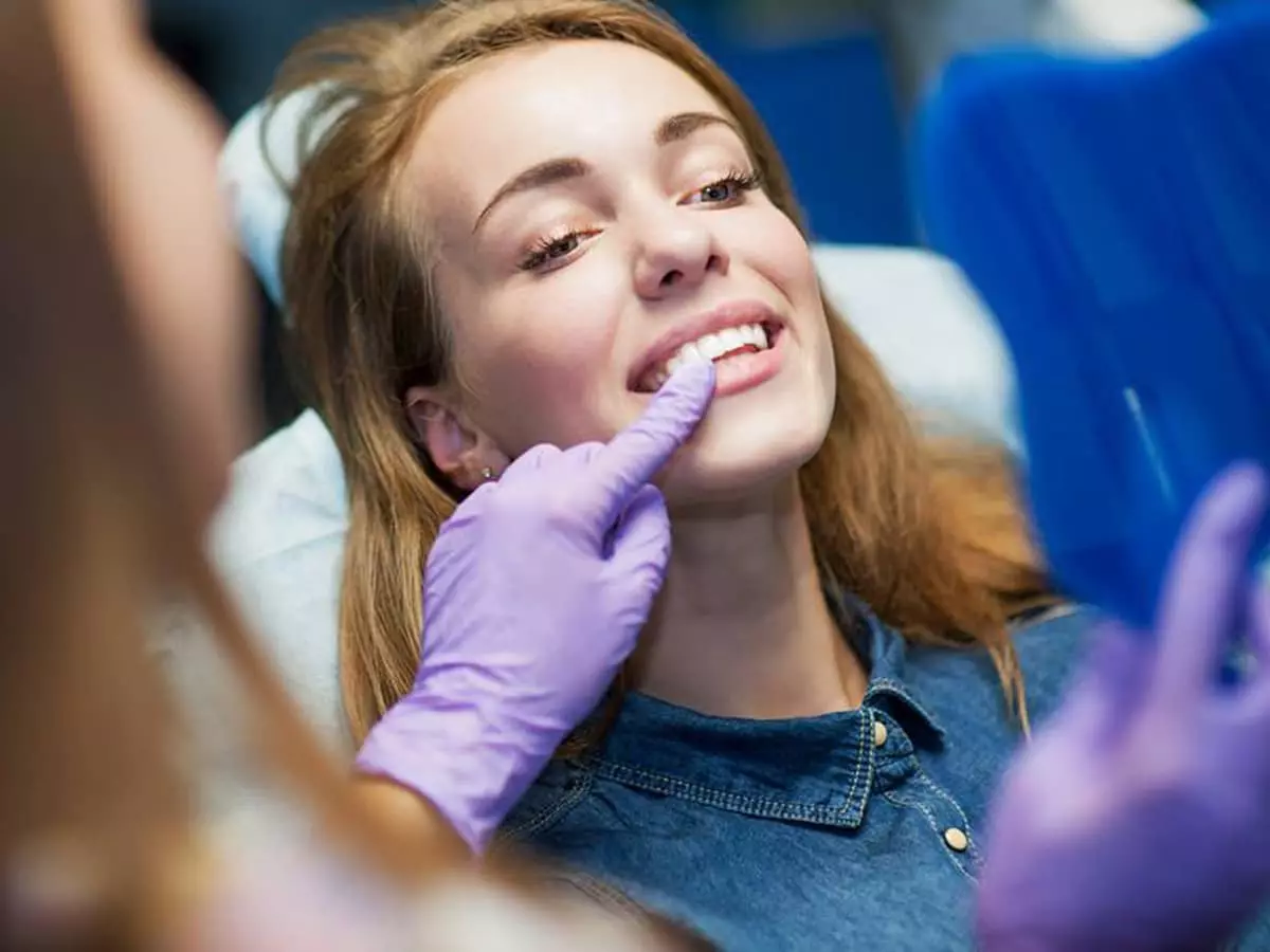 אישה על כיסא רופא שיניים בשיפור שיניים