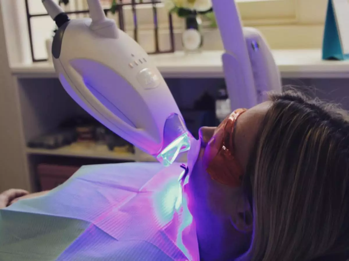 زنی که درمان سفید کننده دندان را با لبخندهای زیبا انجام می دهد